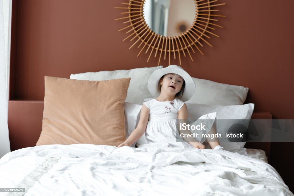 Una Niña Está Sentada En La Cama Con Un Sombrero Puesto Un Niño Con