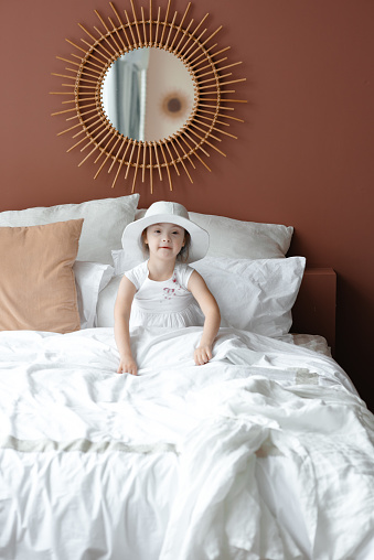 Una Niña Está Sentada En La Cama Con Un Sombrero Puesto Un Niño Con