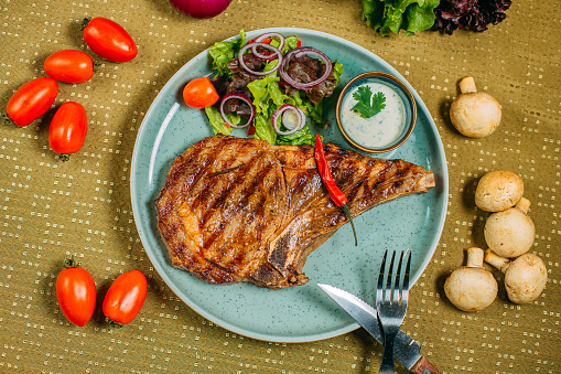 Steak Dengan Sayuran Dan Saus Di Atas Piring Di Atas Meja Yang Dihiasi