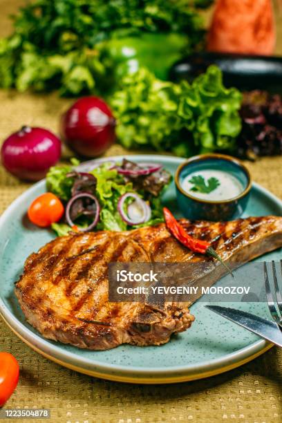 Steak Dengan Sayuran Dan Saus Di Atas Piring Di Atas Meja Yang Dihiasi