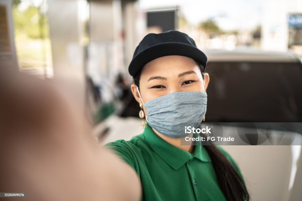 Female Gas Station Attendant Taking A Selfie With Face Mask At Work