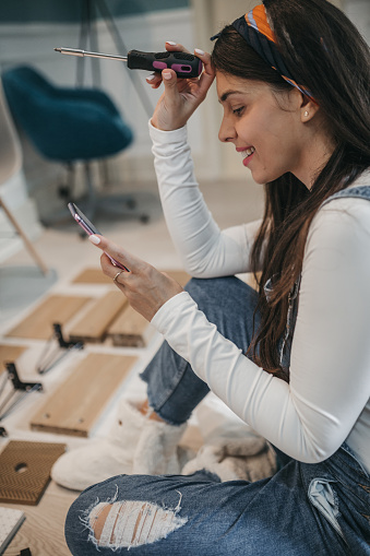 Diy Young Woman Assembling Flat Pack Furniture With A Screwdriver Stock