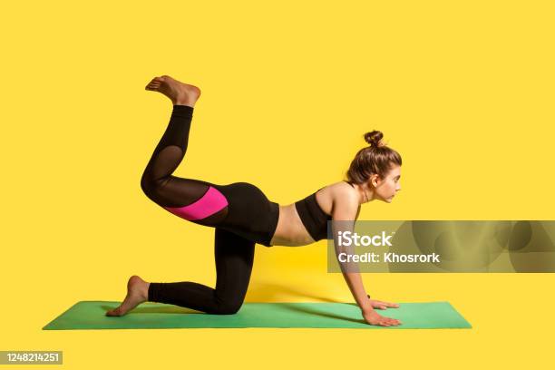 Slim Fitness Woman With Hair Bun In Tight Sportswear Practicing Yoga