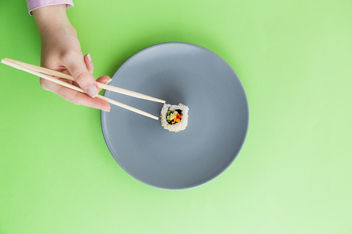 Sudut Pandang Tinggi Wanita Makan Sushi Roll Dengan Sumpit Jepang Diet