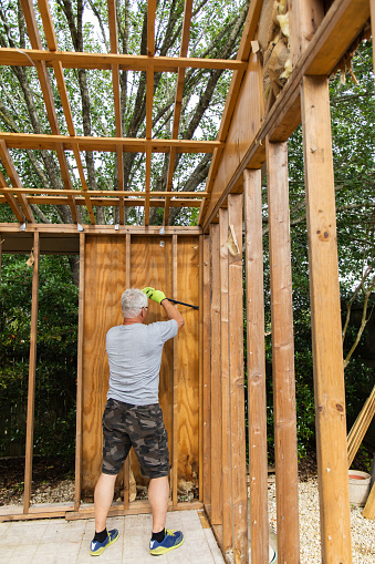 Active Senior Adult Man Tearing Down The Frame Of A Building During The Demolition Process Stock
