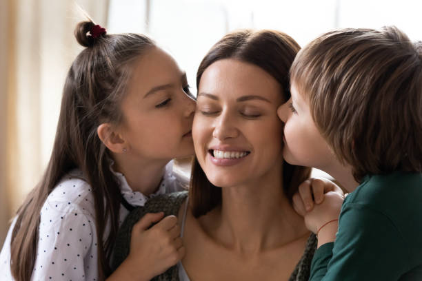 60 Son And Daughter Hugging Mother And Kissing On Her Cheeks Stock