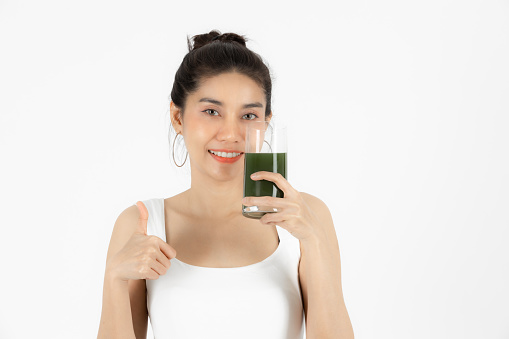 Healthy Young Asian Woman Drinking Green Detox Vegetable Smoothie Over