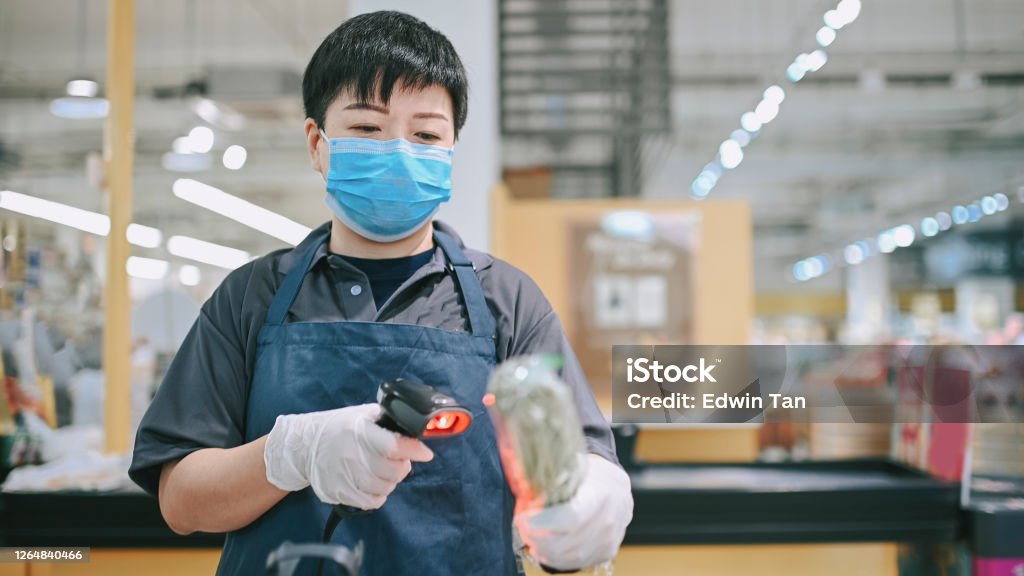 An Asian Chinese Female Supermarket Retailer Shop Assistant Cashier Scanning Vegetable For The