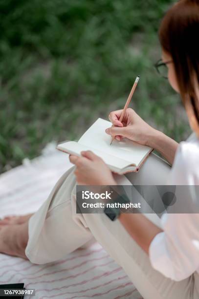 Wanita Muda Menulis Di Notepad Dengan Pensil Sambil Duduk Di Luar