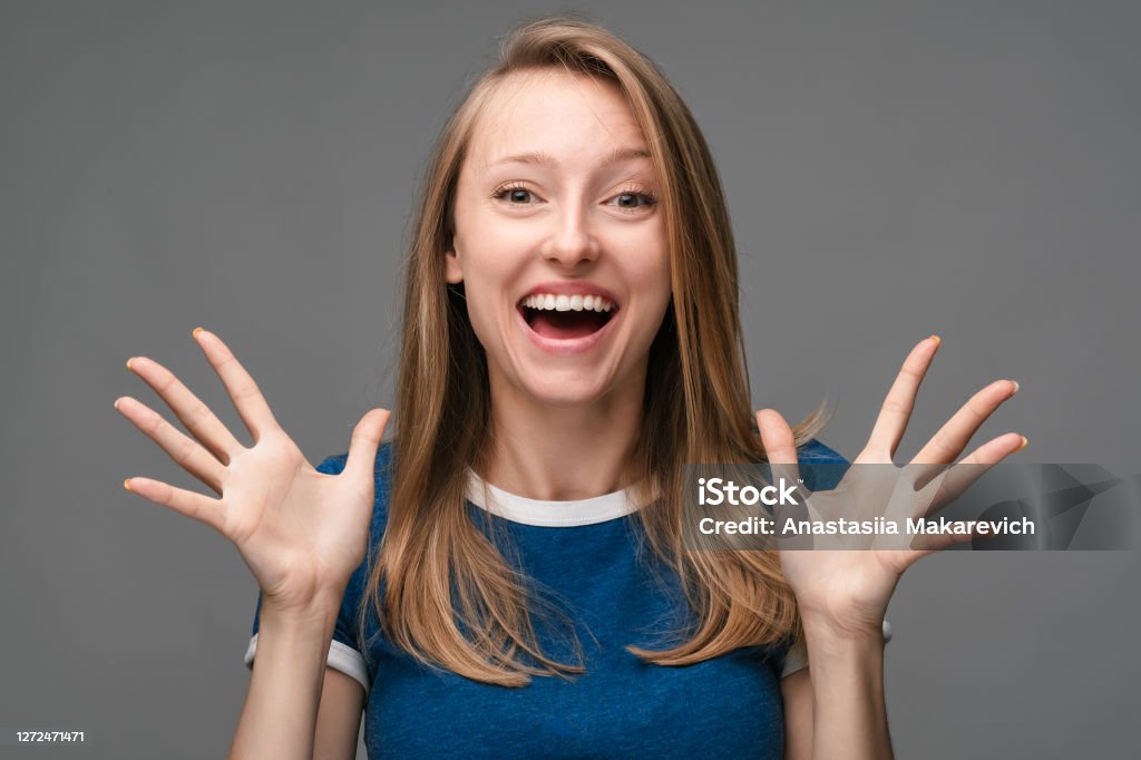Portrait Of Young Female Smiling Happily And Spreads Her Hands To The