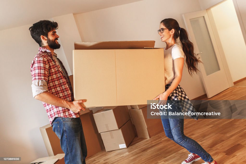 Young Couple Carrying Big Cardboard Full Of Home Essentials Into A New