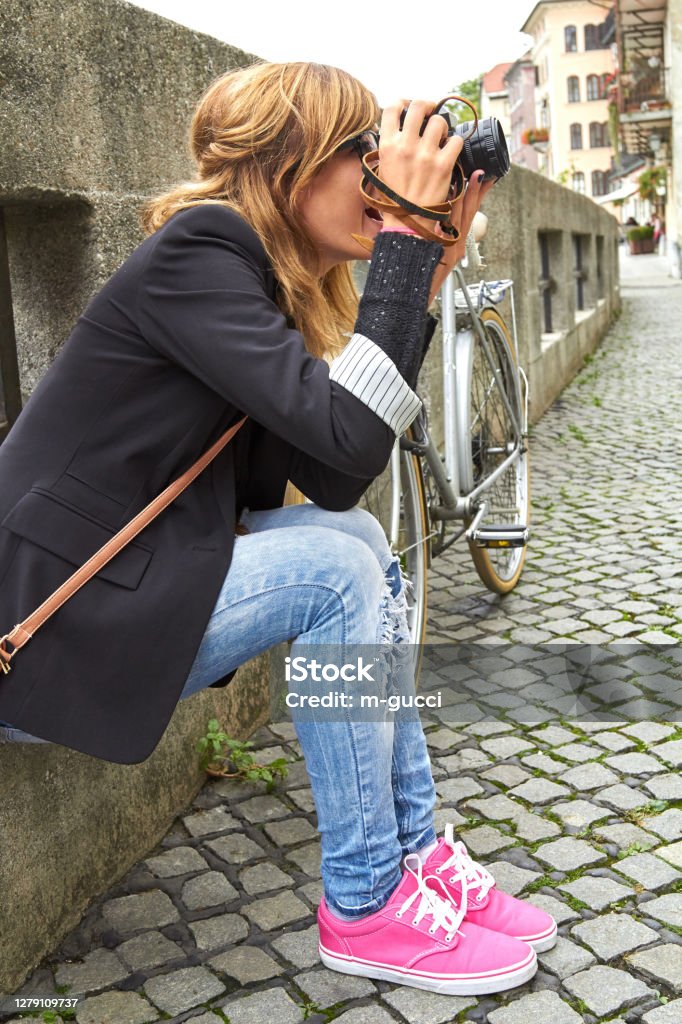 Ung Vit Kvinna Med Gammal Cykel Som Håller Vintagekamera Och Tar Bilder ... Ung Vit Kvinna Med Gammal Cykel Som Håller Vintagekamera Och Tar Bilder ...