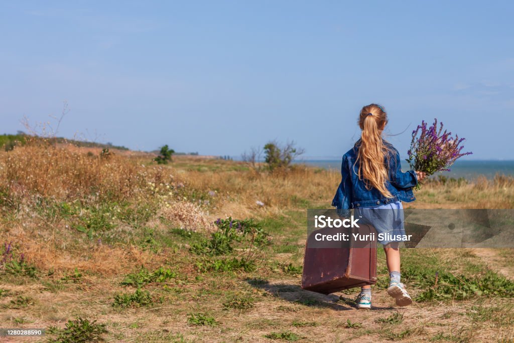 Little Blonde Girl In Denim Jacket Blue Dress With Vintage Suitcase And Flowers Bouquet Offroad