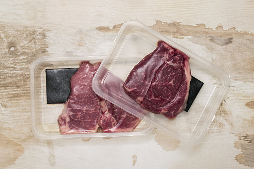 Dua Paket Vakum Dengan Steak Daging Sapi Dengan Latar Belakang Kayu