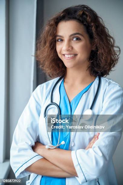 Potret Vertikal Dokter Wanita Muda Mengenakan Tersenyum Dan Melihat Ke
