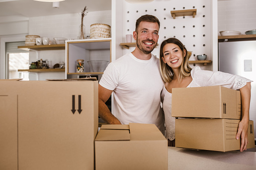 Young Couple Carrying Big Cardboard Box At New Homemoving House Stock