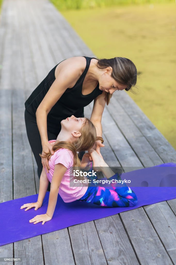 Mom Helps Her Daughter Do Gymnastic Exercises On A Sunny Summer Morning