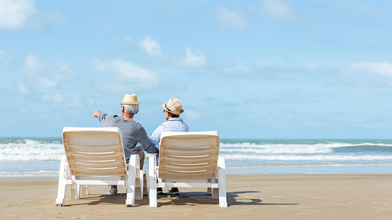 Asian Lifestyle Senior Couple Hug And Pointing On The Beach Happy In