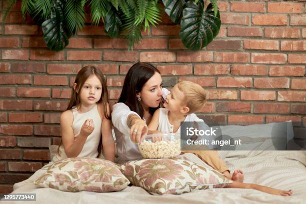 Photo Libre De Droit De Maman Sassoit Sur Le Lit Avec Son Fils Et Sa Fille Et Regarde Un Film