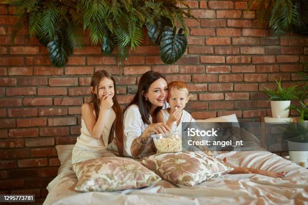 Photo Libre De Droit De Maman Sassoit Sur Le Lit Avec Son Fils Et Sa Fille Et Regarde Un Film