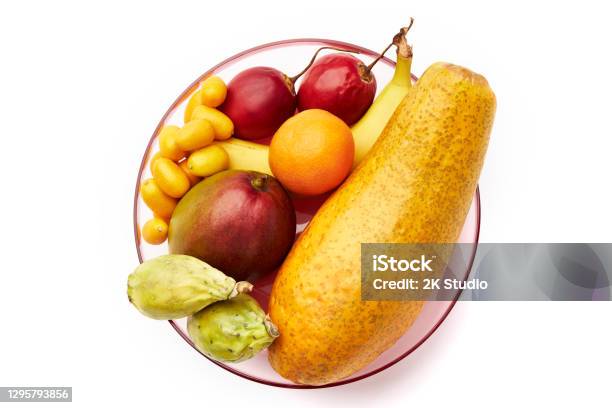 A Modern Pink Fruit Bowl Made Of Glass Filled With Exotic Fruits Photographed Against A White