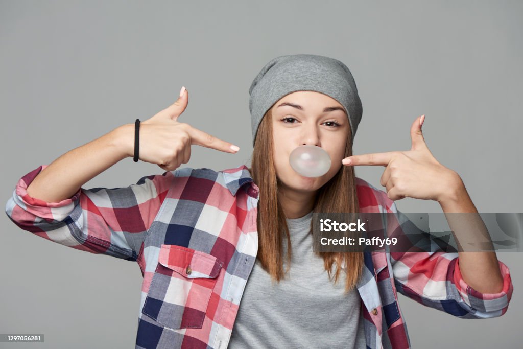 Closeup Of Cheeky Teen Girl Blowing Bubblegum And Pointing At It Stock