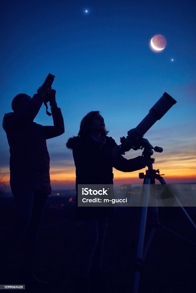 Mother And Daughter Observing Stars Planets Moon And Night Sky With