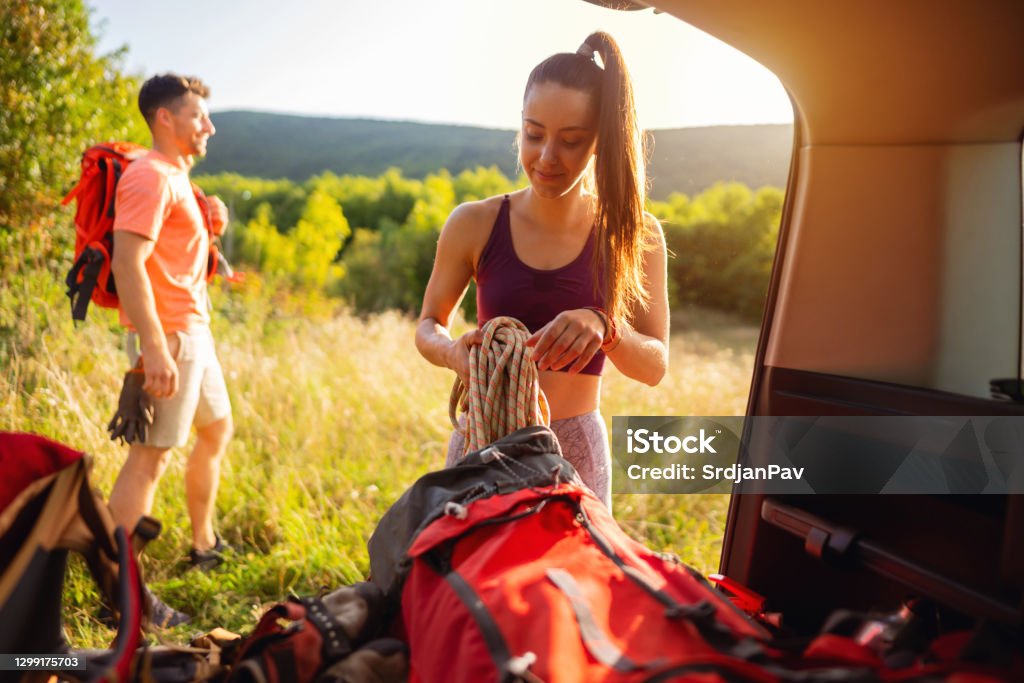 Woman Packing Climbing Rope Into A Backpack In The Car Trunk Stock