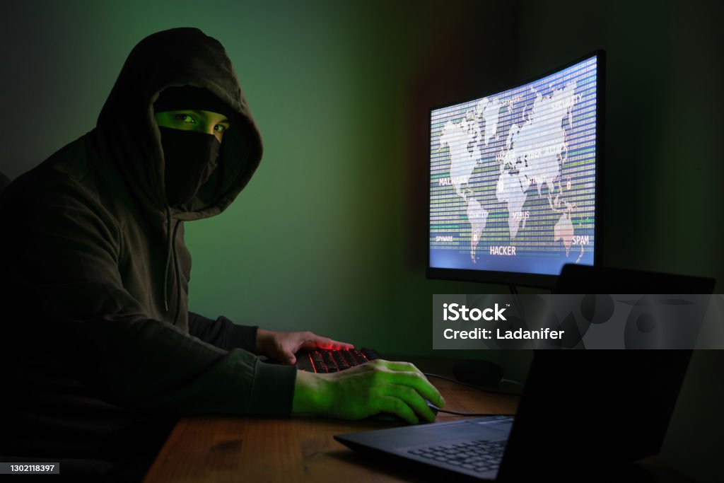 Maskierte Hacker Die Auf Die Kamera Schauen Verwendet Einen Computer Um ... Maskierte Hacker Die Auf Die Kamera Schauen Verwendet Einen Computer Um ...