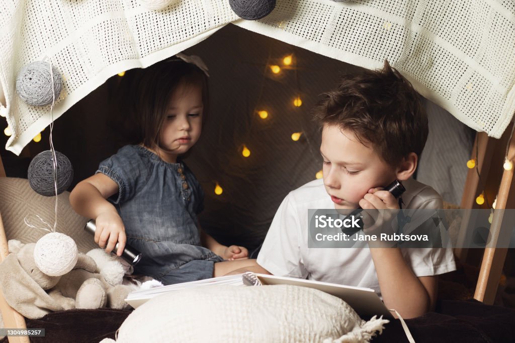 Siblings Lie In Hut Of Chairs And Blankets Brother And Sister Reading