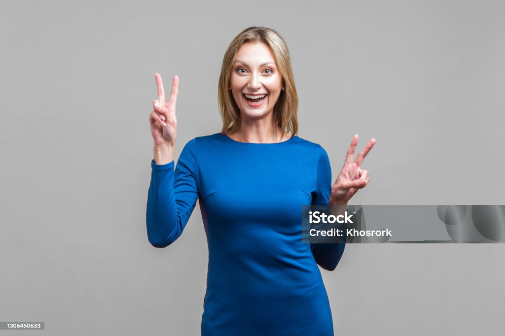 Portrait Of Joyous Beautiful Woman Showing Victory Gesture With Both
