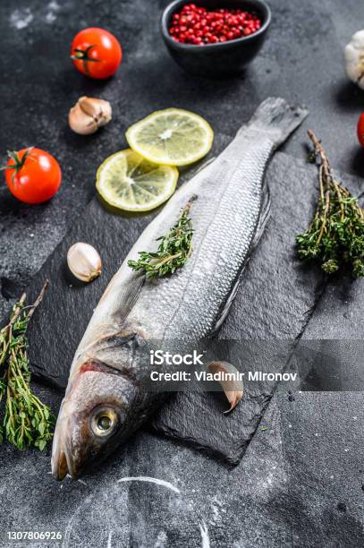 Ikan Bass Laut Segar Dengan Bumbu Dan Lemon Di Atas Piring Hitam Latar
