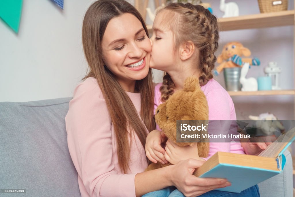 Mother And Daughter Together At Home Woman Reading Book To Girl Stock
