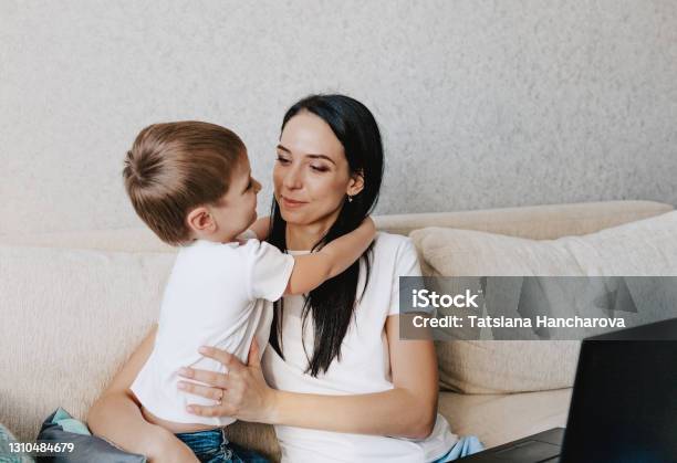 Ibu Bahagia Memeluk Putranya Yang Masih Kecil Sambil Duduk Di Sofa Di