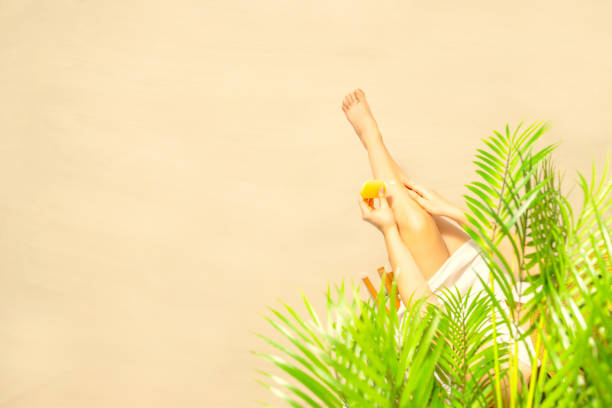 70 Woman Applying Sunscreen On Her Legs At A Caribbean Beach Stock