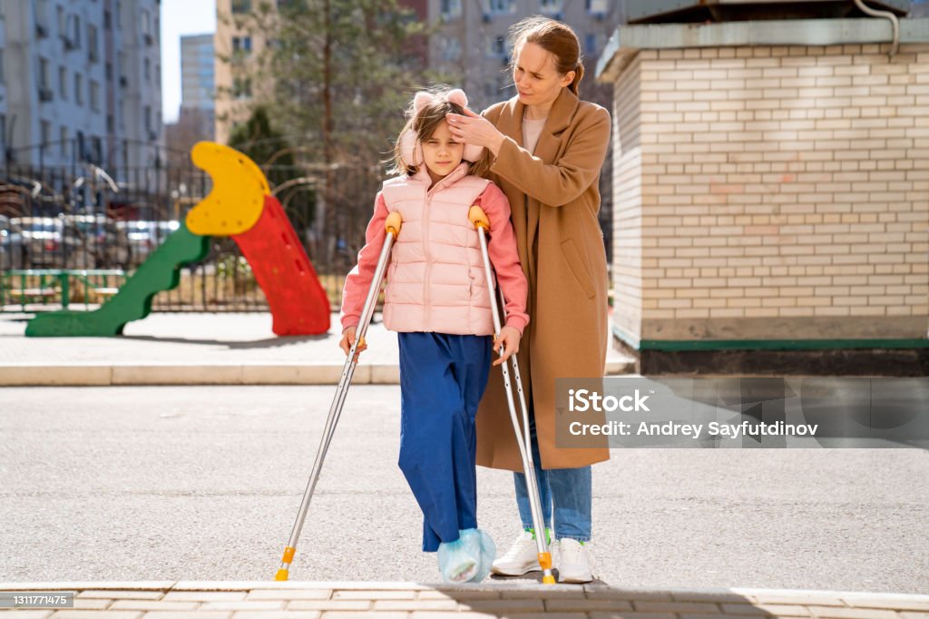 Mom Helps Daughter Learn To Walk On Crutches Plaster On Your Feet Stock