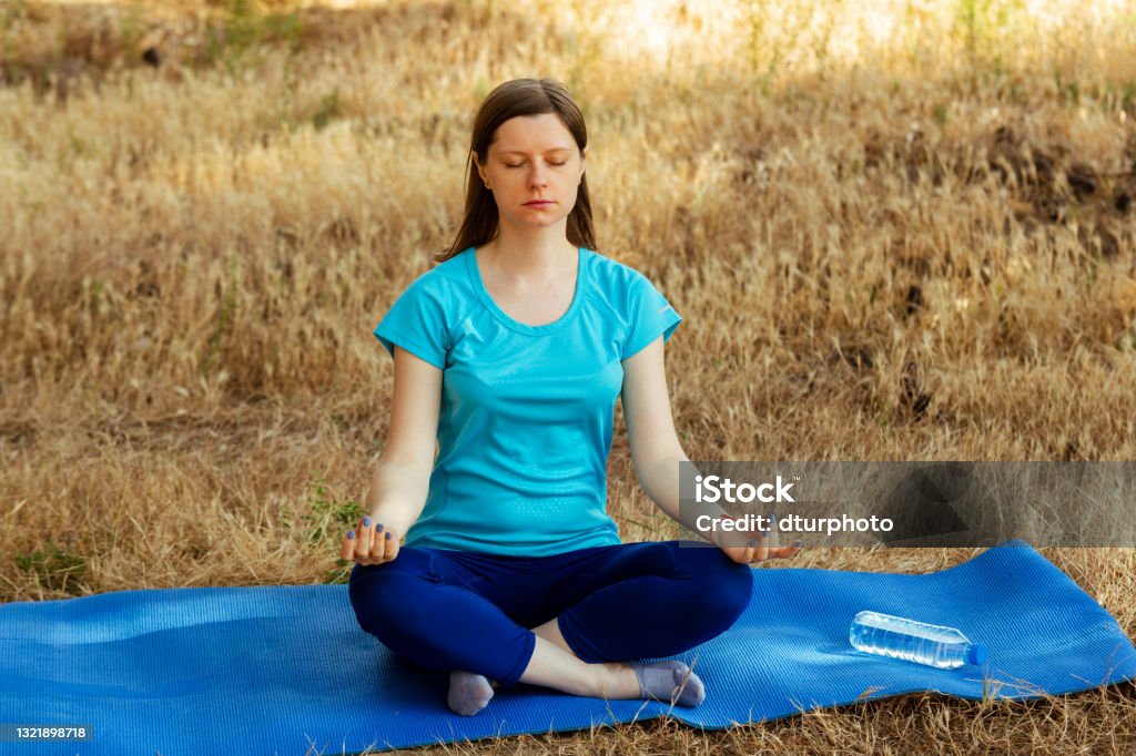 Pregnant Woman Doing Yoga Exercises Outside In The First Trimester Of