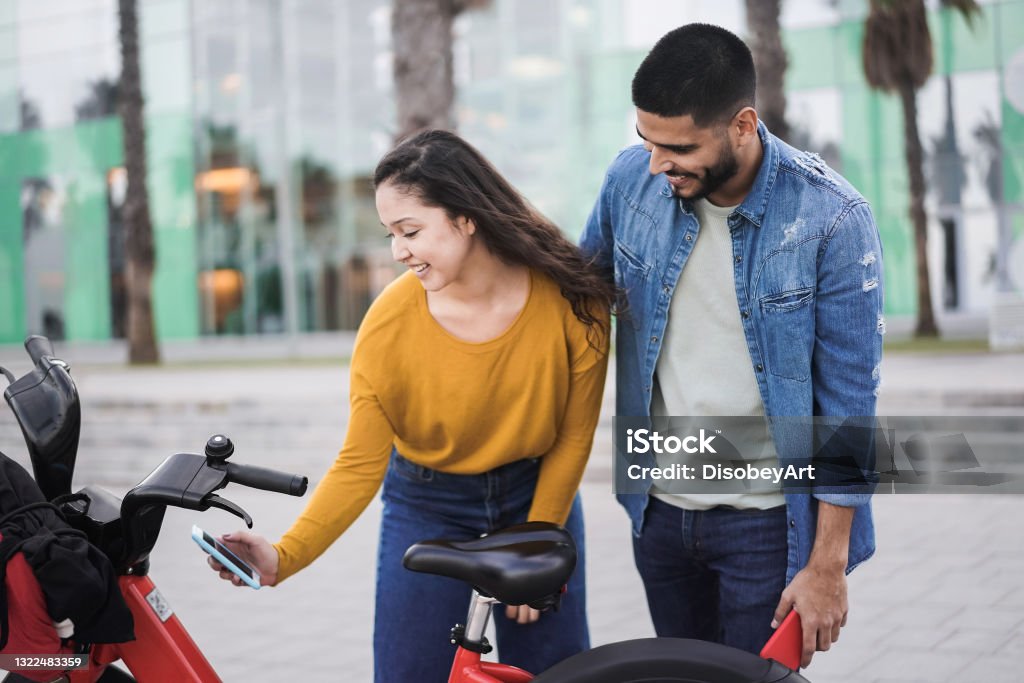 Young People Renting Electric Bicycle With Smartphone App Focus On Man