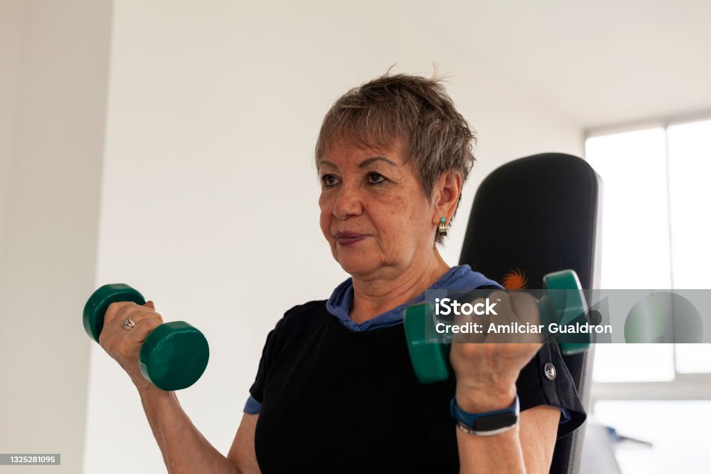 70yearold Latina Grandmother Works Out Lifting Weights In A Gym Stock