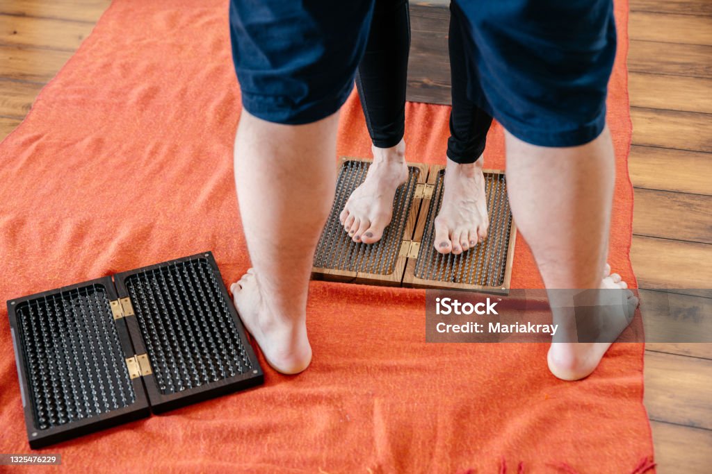 Man Trainer Helping Woman To Stand On Sadhu Yoga Board Barefoot On A