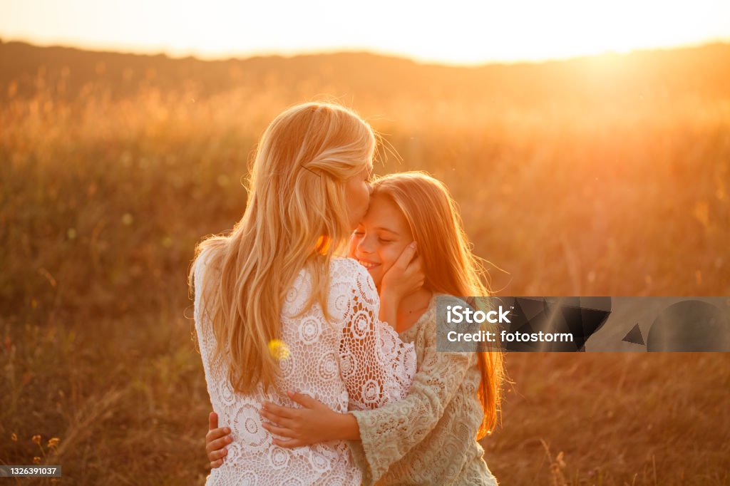 Mother And Daughter Embracing And Kissing Bonding During Summer Sunset