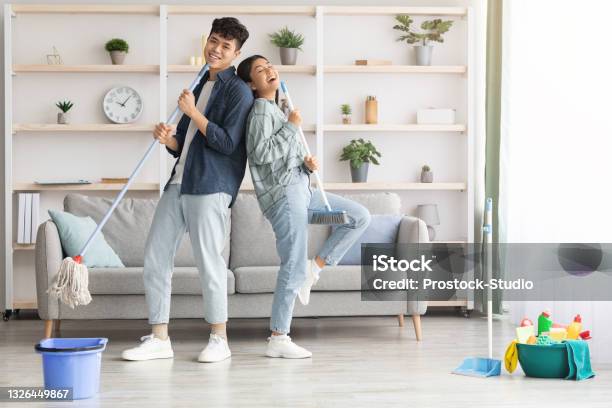 Happy Asian Couple Singing Songs While Cleaning Apartment Copy Space