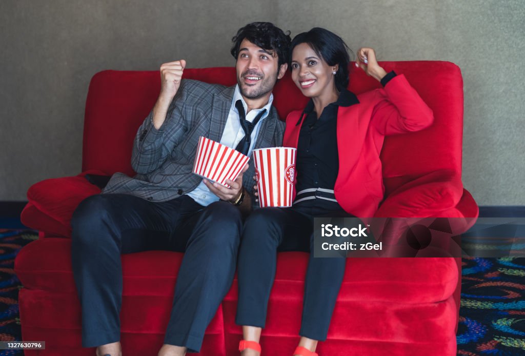 Happy Diverse Couple Eating Popcorn While Watching Movie At The Cinema