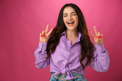 Happy Smiling Woman Showing Victory Sign Against Pink Background Stock