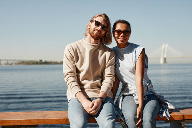 Free Stock Photo of Couple sitting on bridge railing overlooking river ...