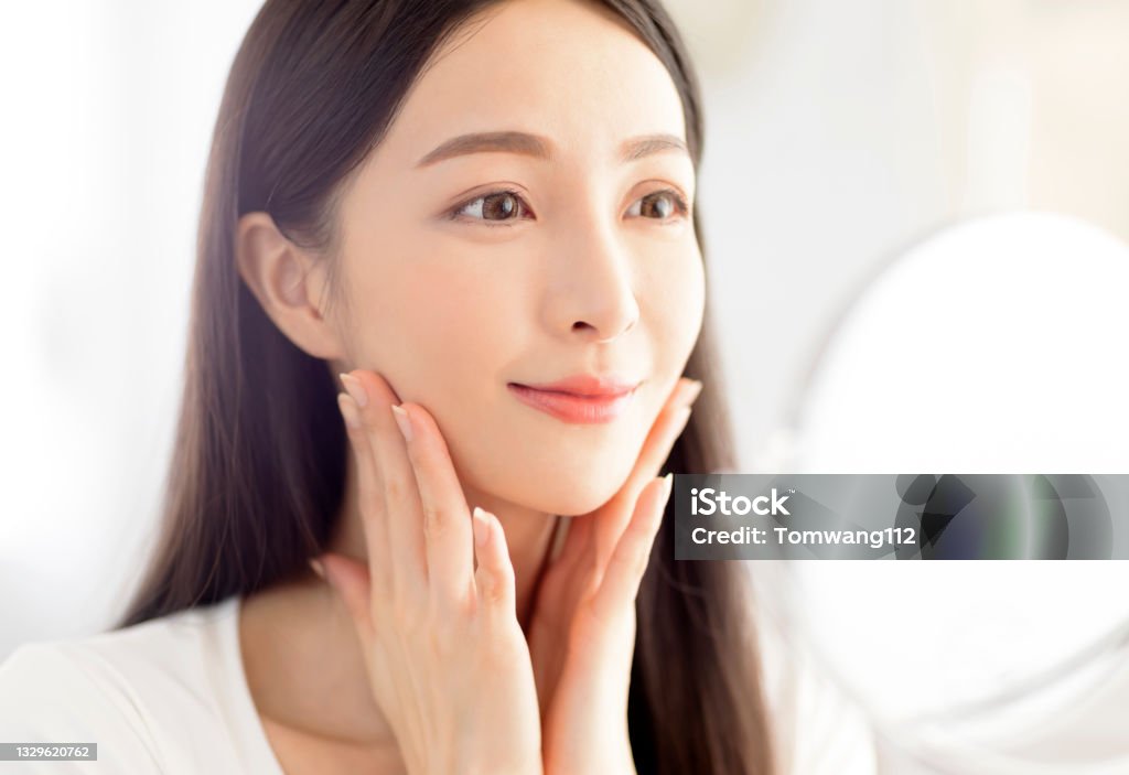 Beautiful Young Woman Touching Face Skin And Looking In Mirror Stock