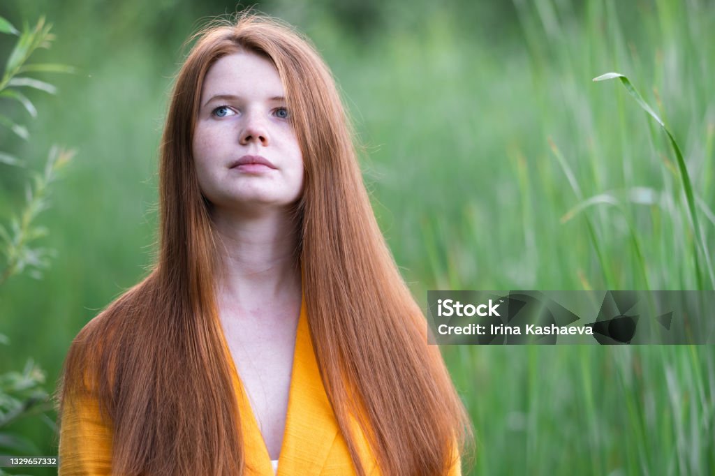 Portrait Of A Beautiful Redhaired Girl In The Green Grass In Summer