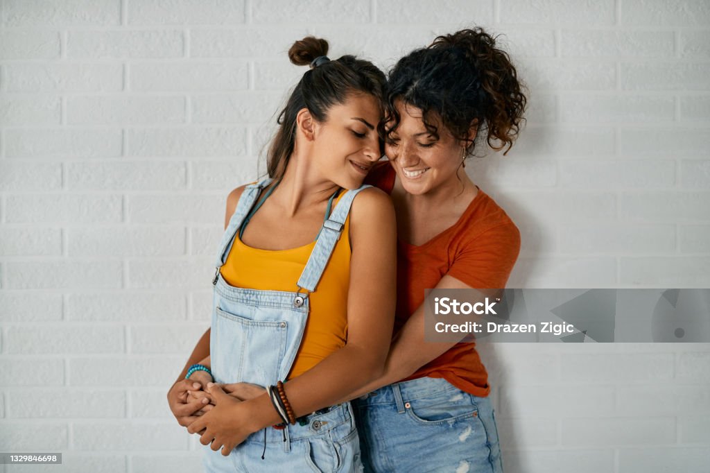 Young Happy Lesbian Couple In Love Embracing Against The Wall Stock