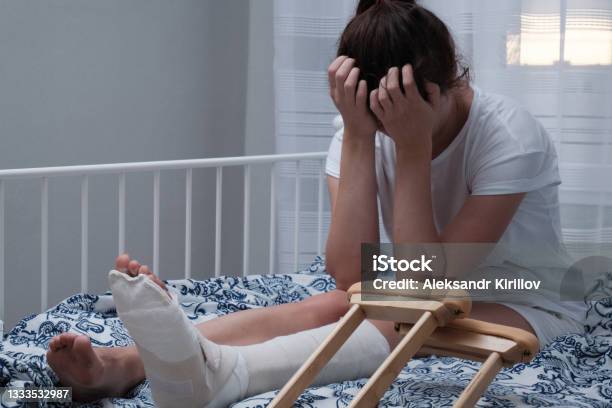 Photo Libre De Droit De Une Femme Avec Un Plâtre Sur La Jambe Sassoit Sur Le Lit Pleure Et