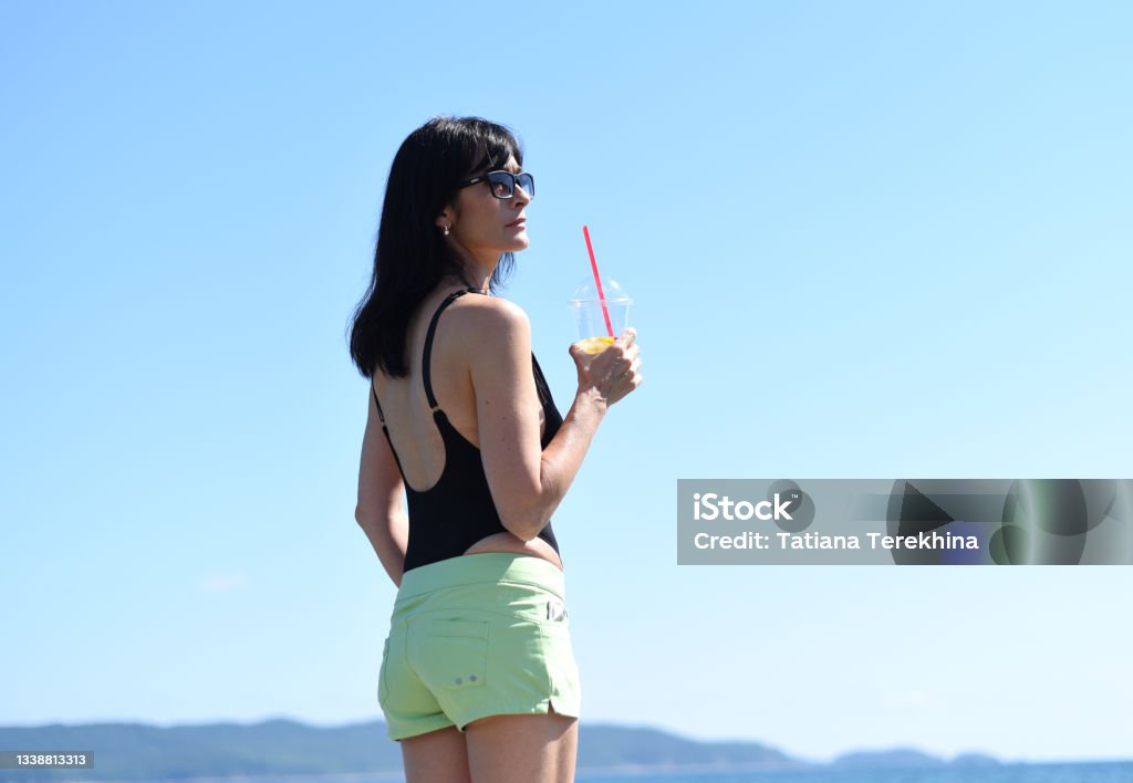 45 Years Old Russian Woman Drinking Lemonad And Standing Against Blue